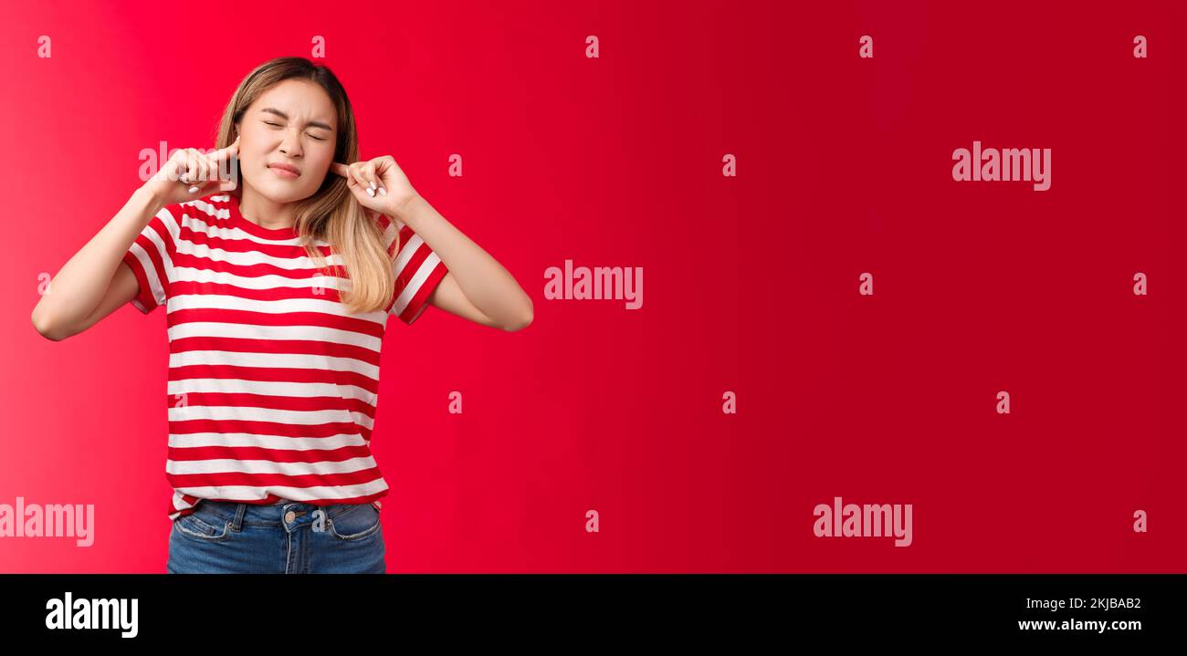 Gosh awful noise. Distracted and displeased blond korean girl grimacing ...