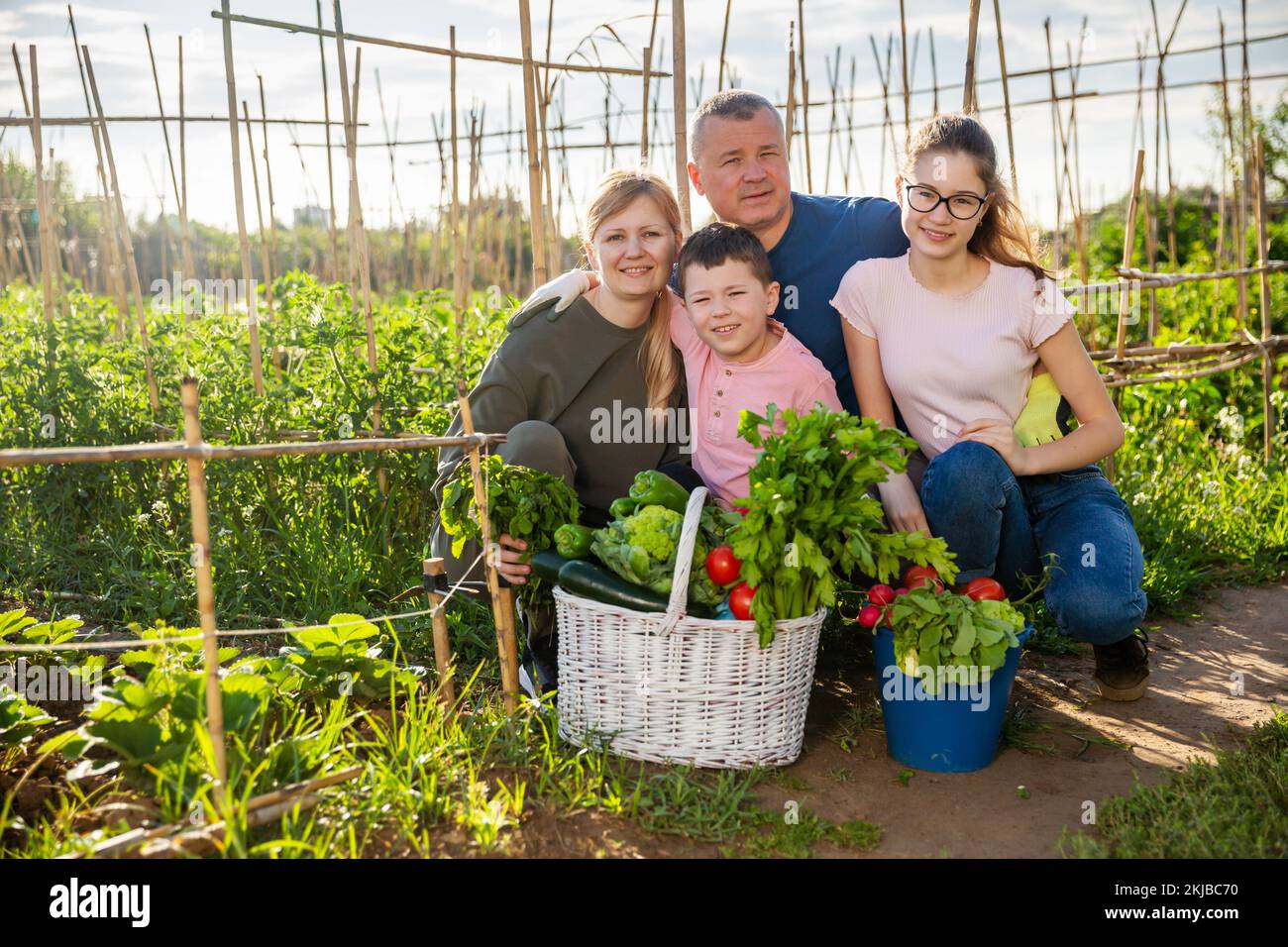 Happy family standing with crop of vegetables in garden Stock Photo - Alamy