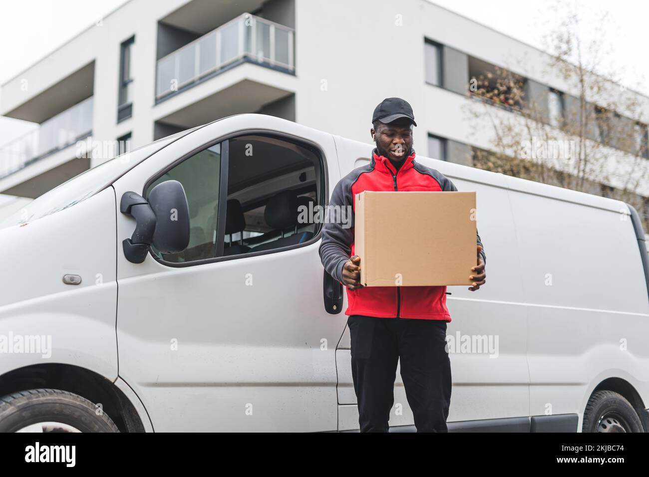 Black young adult delivery man wearing work uniform standing outside of ...