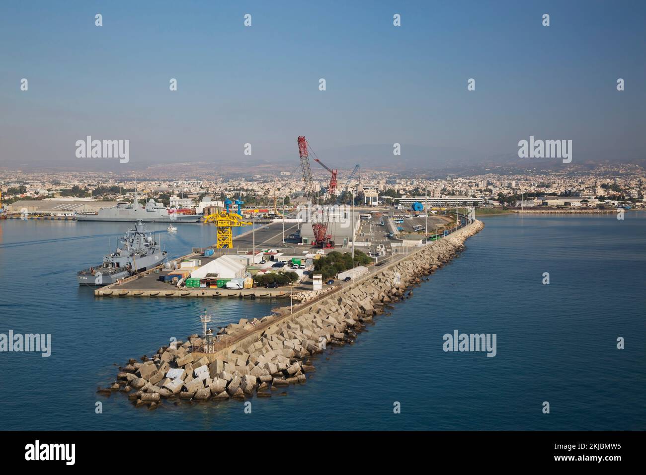Docked warship at wharf with gantry cranes and man-made breakwater in ...