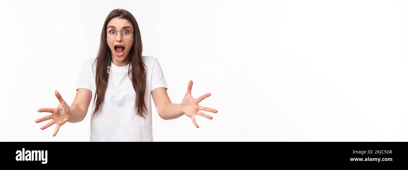 Watch out. Alarmed and shocked, scared pretty girl raising hands to ...