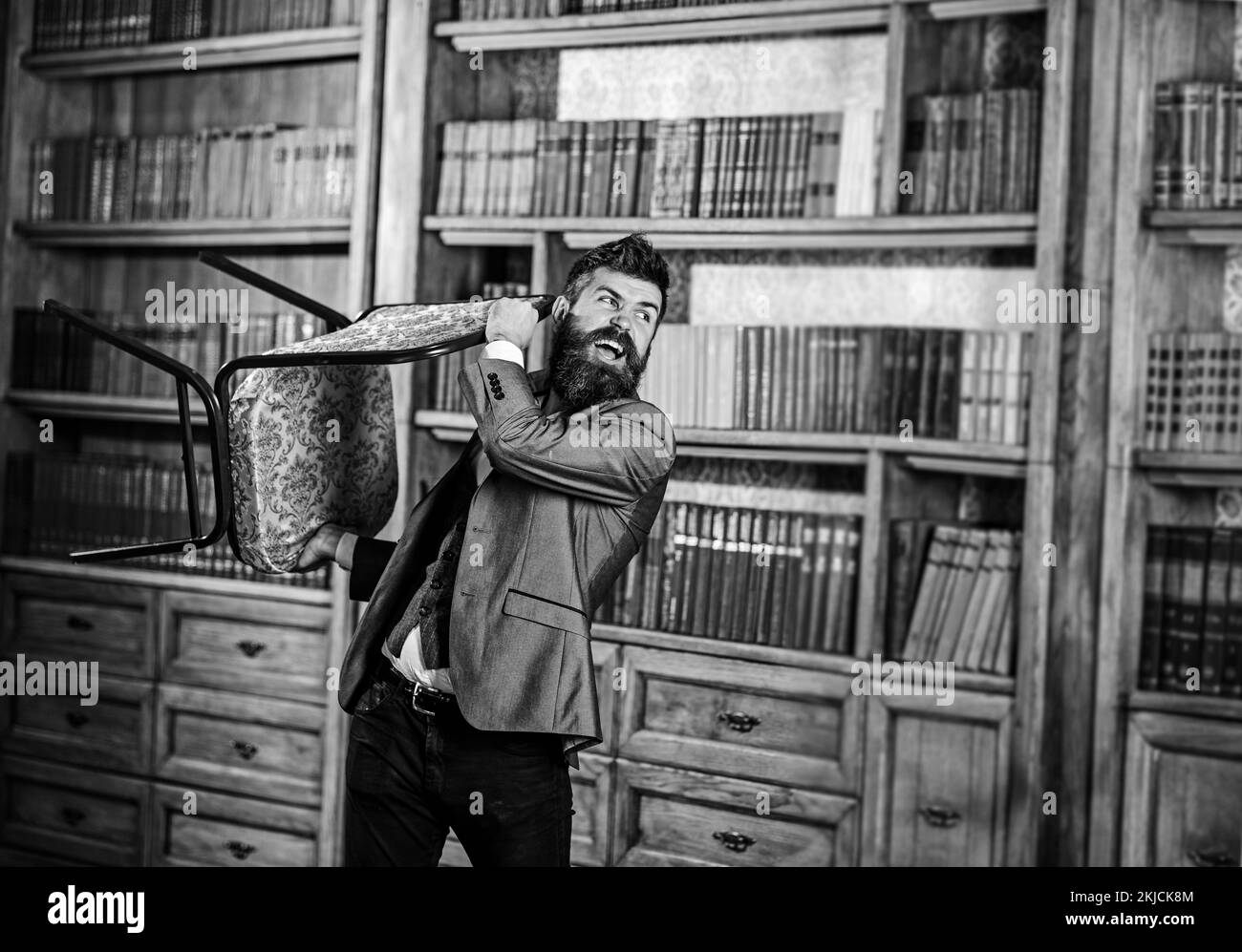 Bearded man wearing formal outfit. Looking crazy. Over library ...