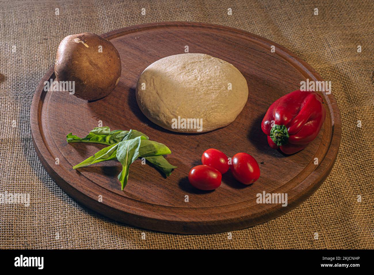 Preparation italian pizza dough with vegetables on table Stock Photo ...