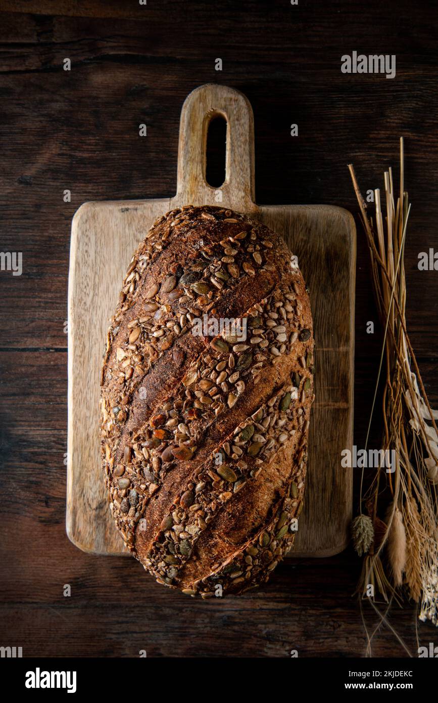 A top view of sourdough bread with whole-grain toppings on a wooden ...