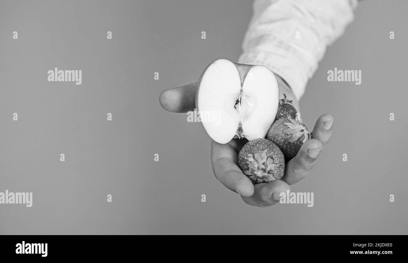 Help yourself. Hand proposes take strawberry and apple fruit. Male hand ...