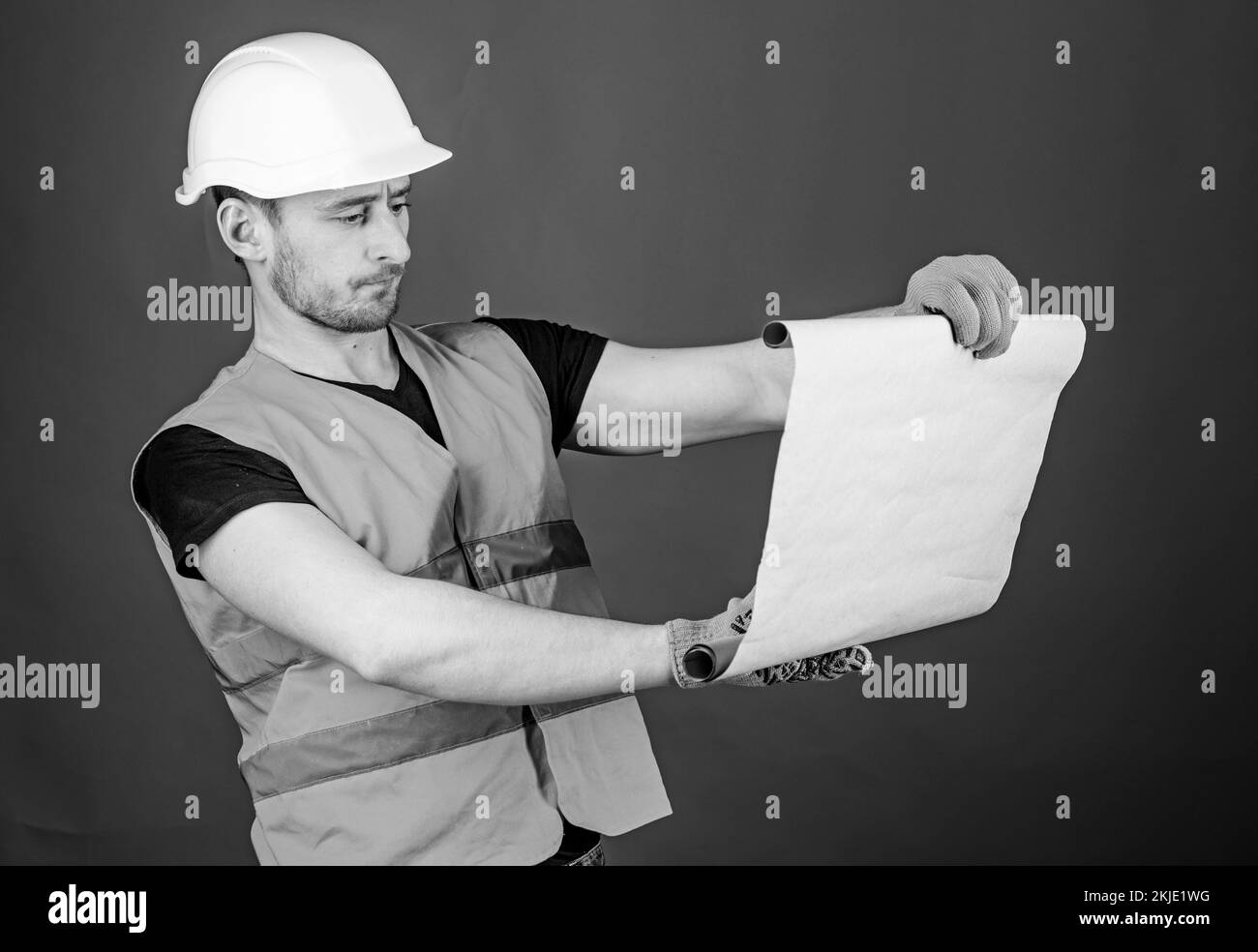 Man in helmet, hard hat holds building plan, controls works, red ...
