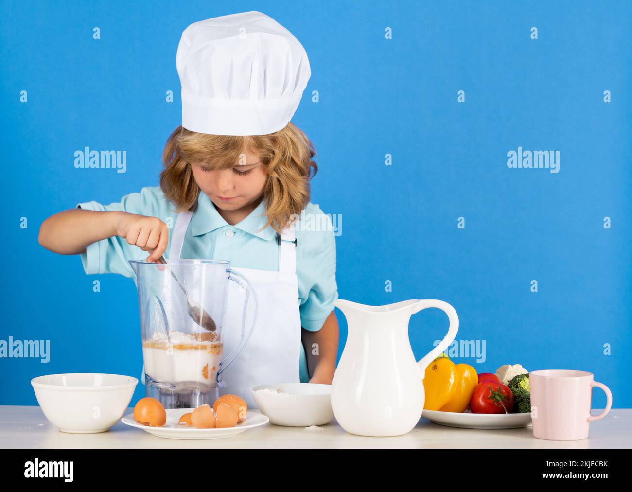 Kid boy in chef hat and apron cooking preparing meal. Little cook with ...