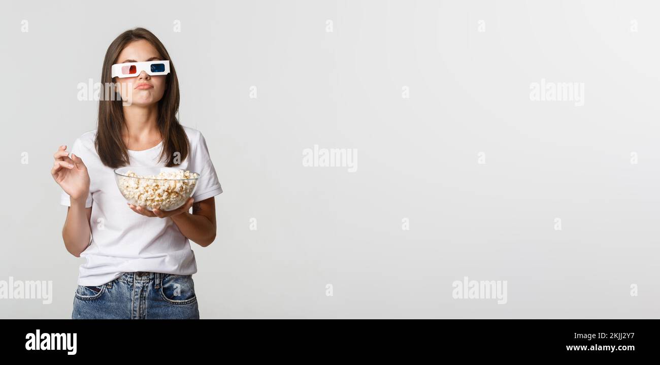 Skeptical beautiful woman in 3d glasses, holding popcorn and looking ...