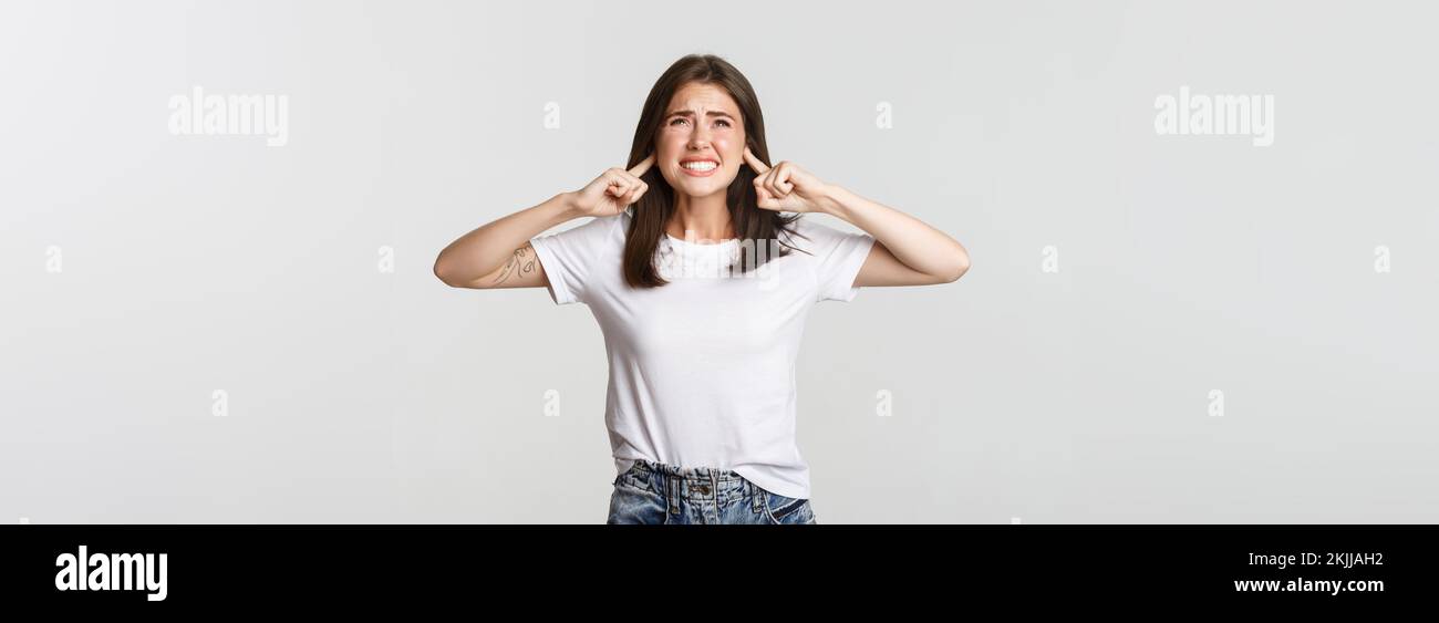 Annoyed and bothered girl shut ears and complaining at loud awful noise ...