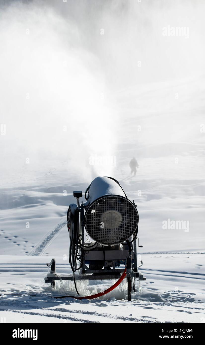 Area worker walking up a run as a snow making machine works at Loon ...