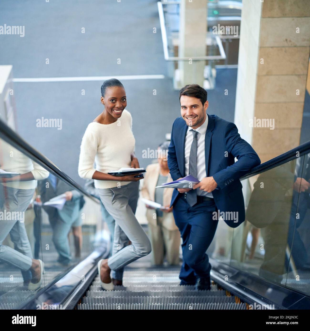 Theyre headed for the top. Full length shot of two young businesspeople taking the escalator ...