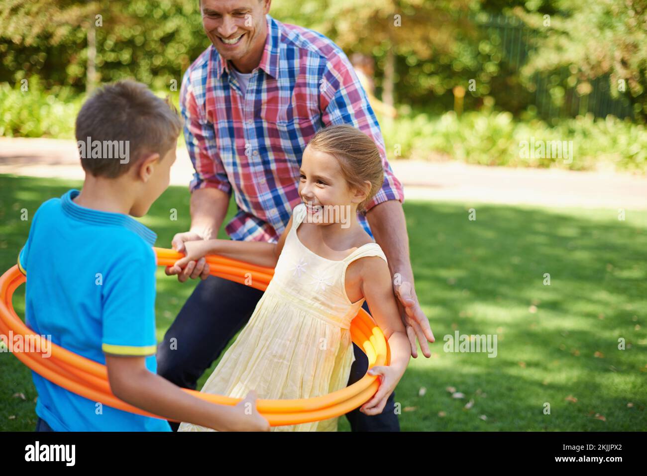 Fun at the park. A happy young family playing with hula hoops on a ...