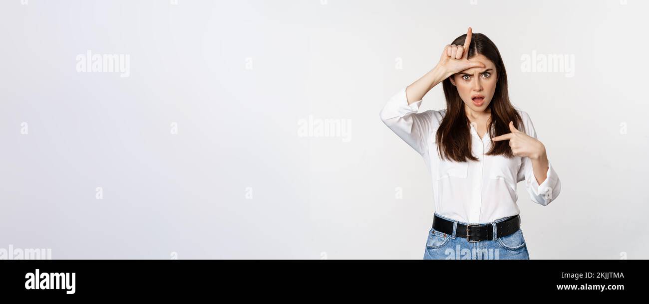 Insulted woman showing loser L word sign on forehead, pointing at ...