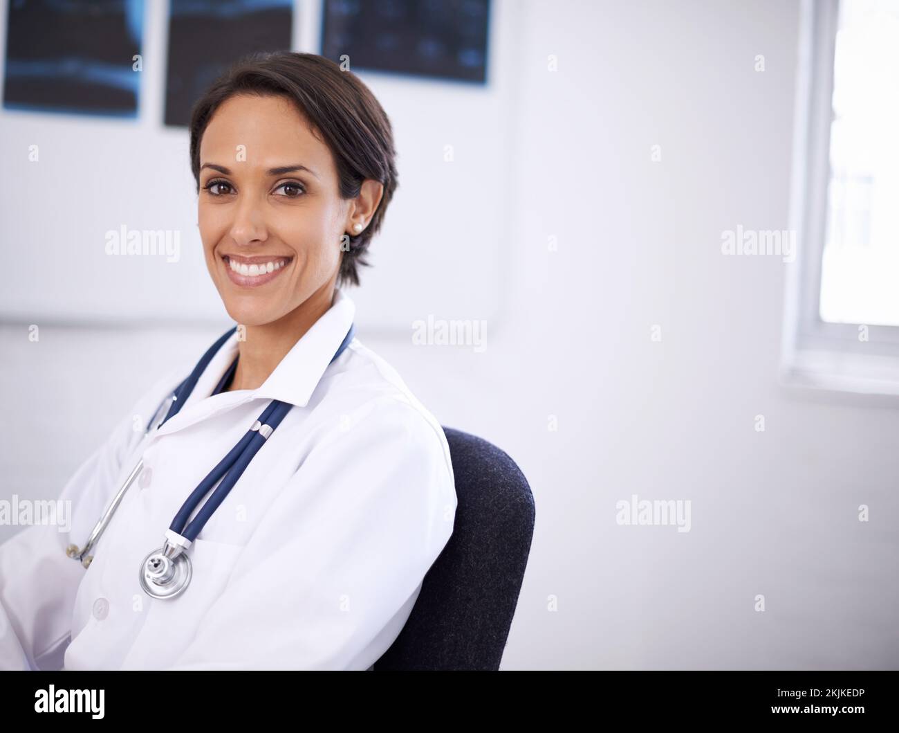Ready for her next patient. Portrait of a happy young doctor sitting at ...