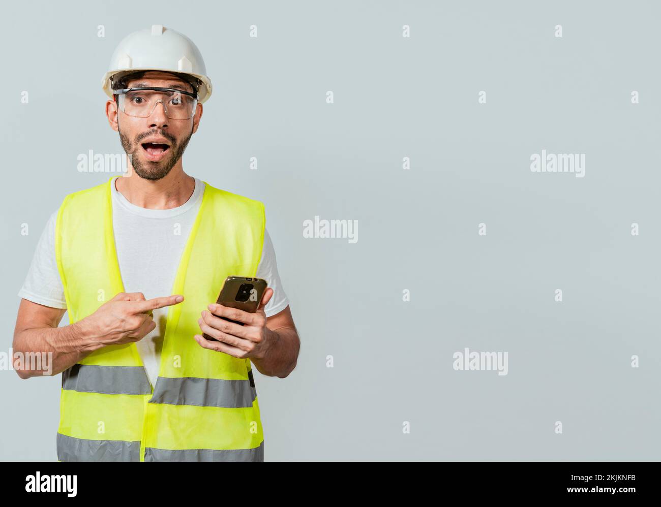 Engineer using and pointing at cellphone. Amazed construction worker ...