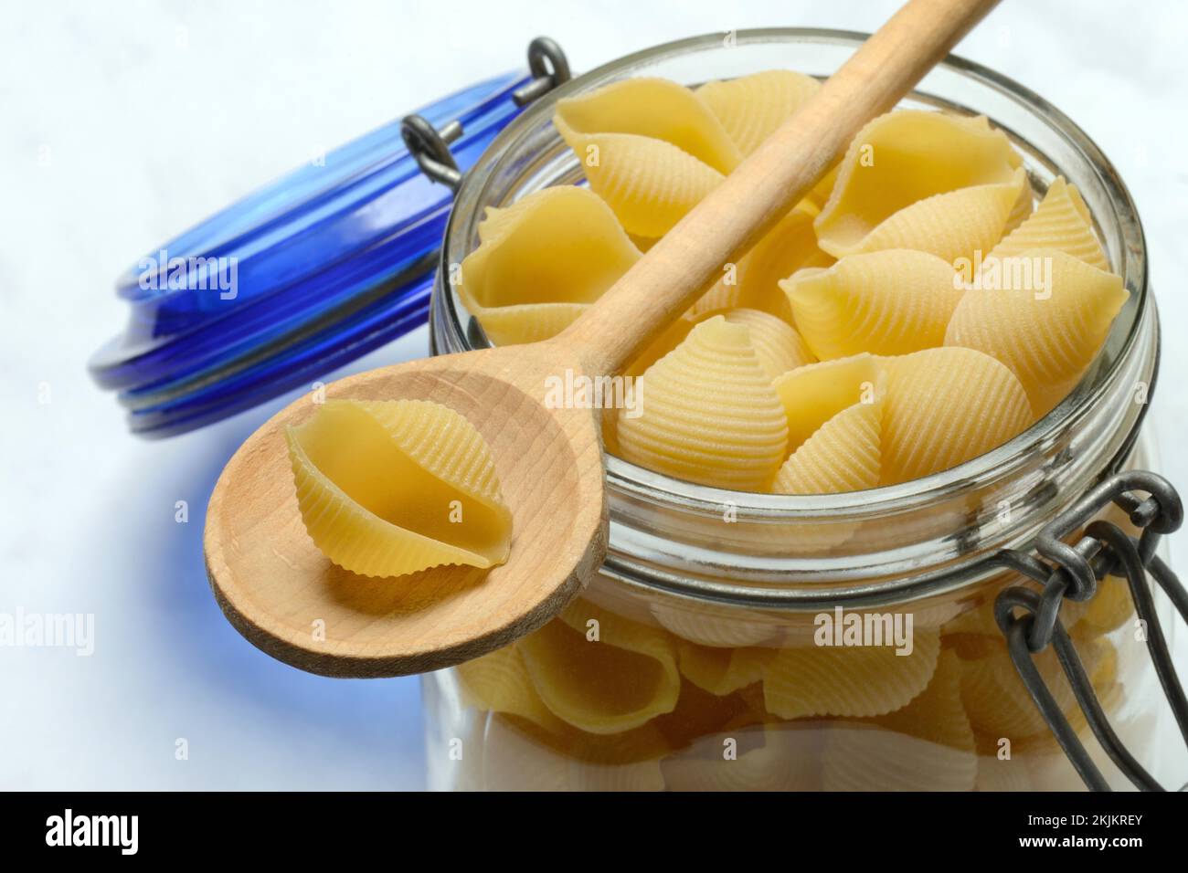 Conchiglie, shell pasta in glass container with cooking spoon, pasta ...