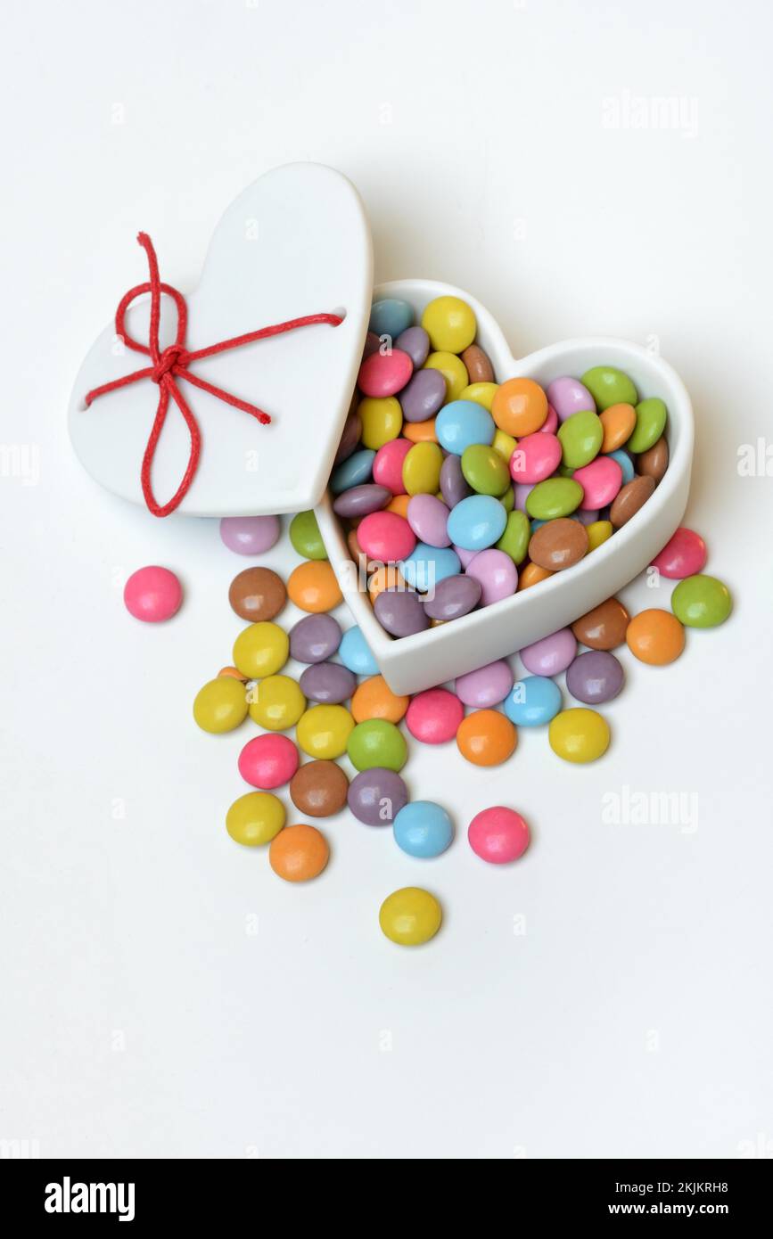 Chocolate lentils in heart-shaped container, Smartie Stock Photo - Alamy