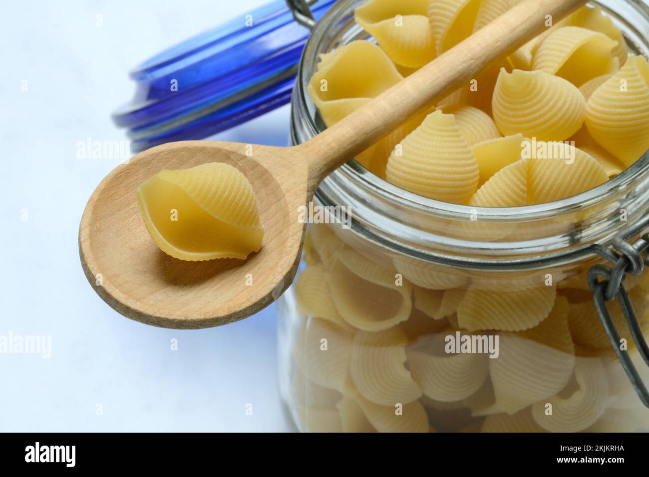 Conchiglie, shell pasta in glass container with cooking spoon, pasta ...