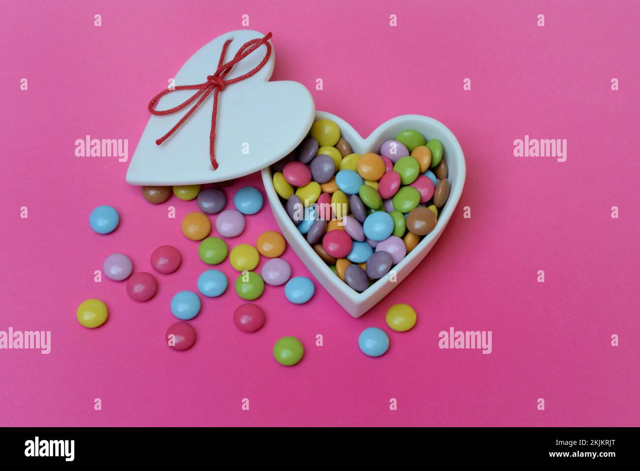 Chocolate lentils in heart-shaped container, Smartie Stock Photo - Alamy