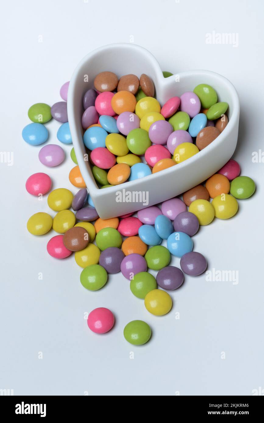 Chocolate lentils in heart-shaped container, Smartie Stock Photo - Alamy