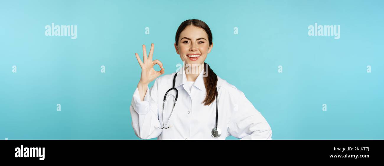 Portrait of satisfied, smiling medical worker, woman doctor showing ...