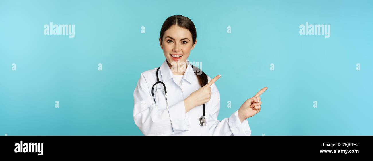 Portrait of smiling medical worker, girl doctor in white coat with ...