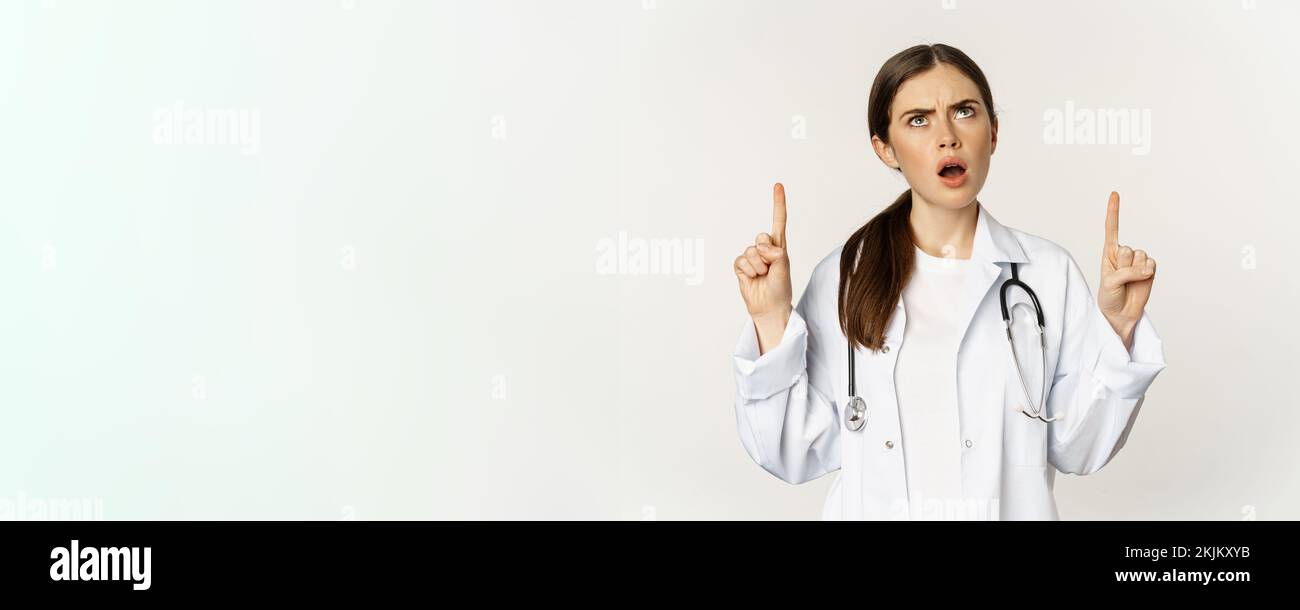 Sad and disappointed female doctor, frowning frustrated, pointing ...