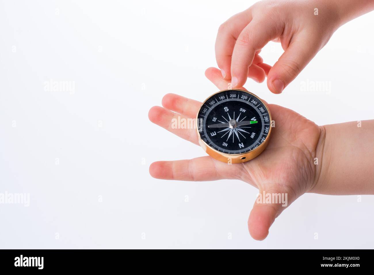 Child hand holding a compass on a white background Stock Photo - Alamy