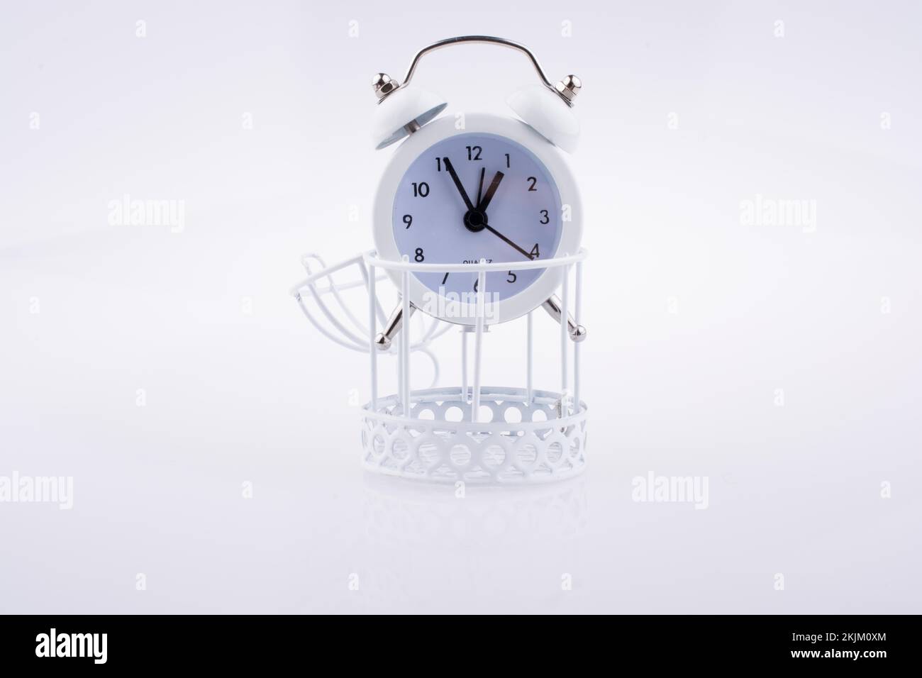 White color alarm clock on bird cage on white background Stock Photo ...
