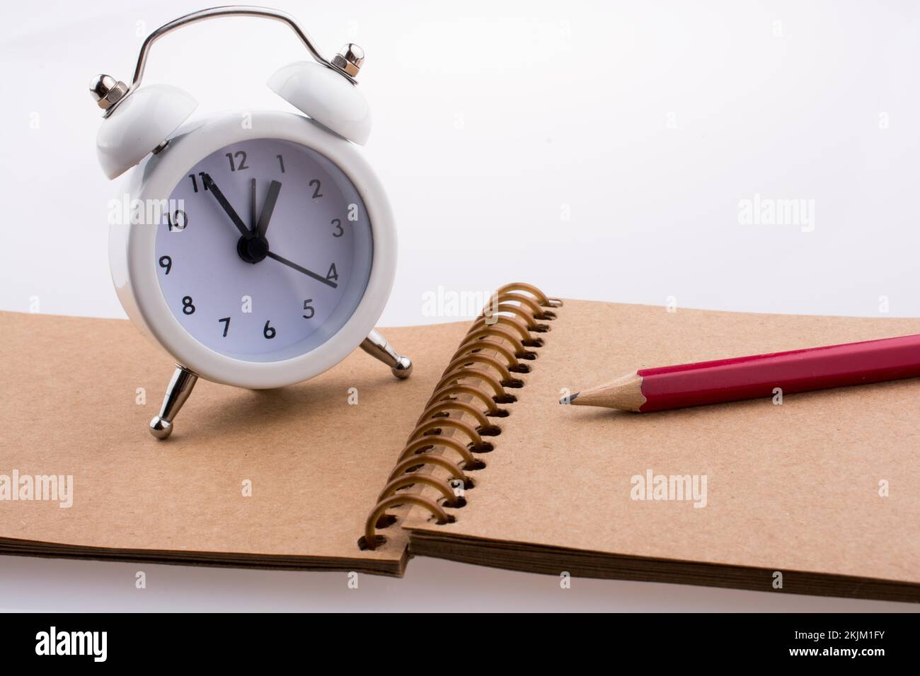 Color pencil and an alarm clock placed on a spiral brown notebook Stock ...