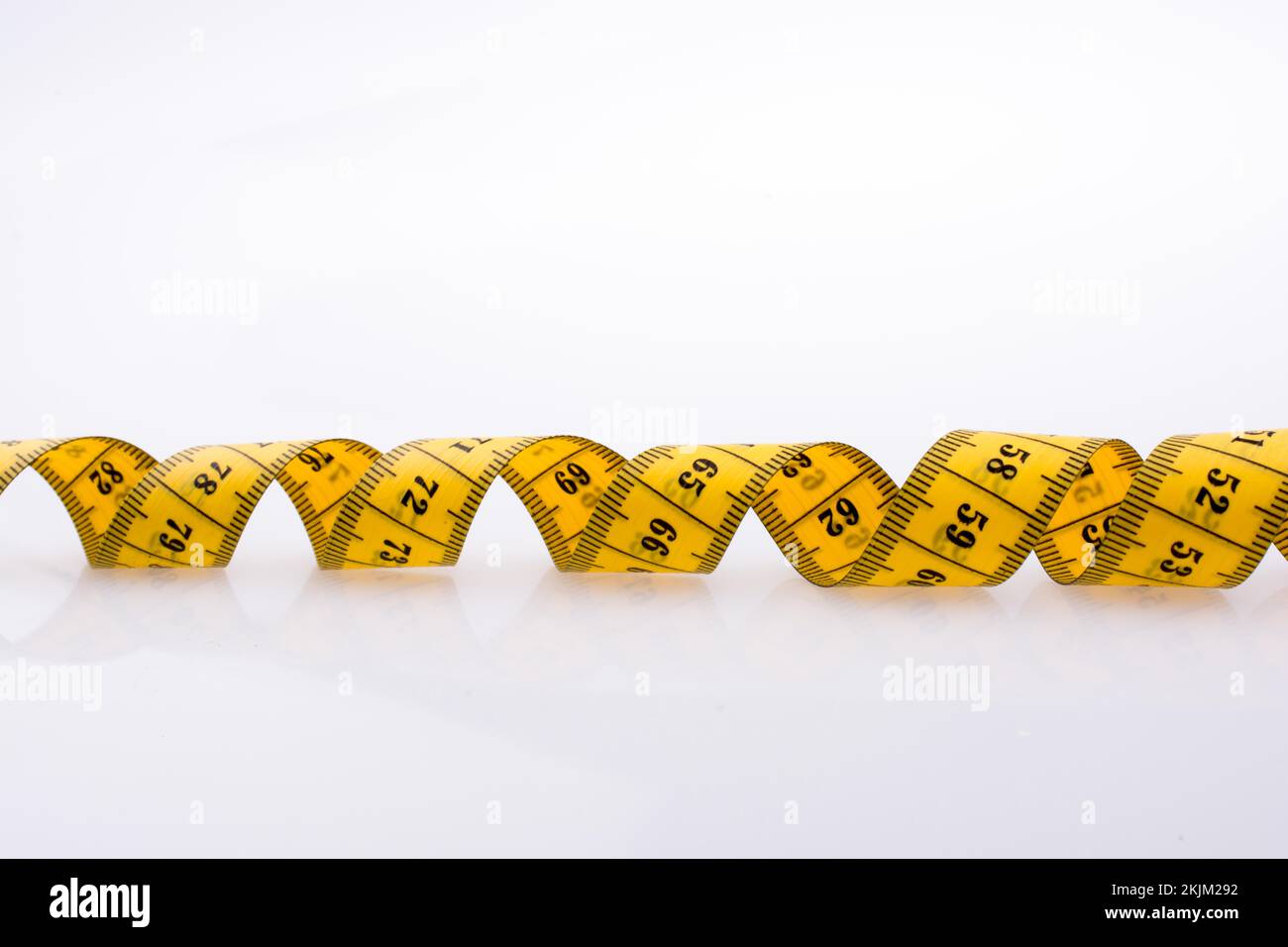 Yellow color measuring tape on a white background Stock Photo - Alamy