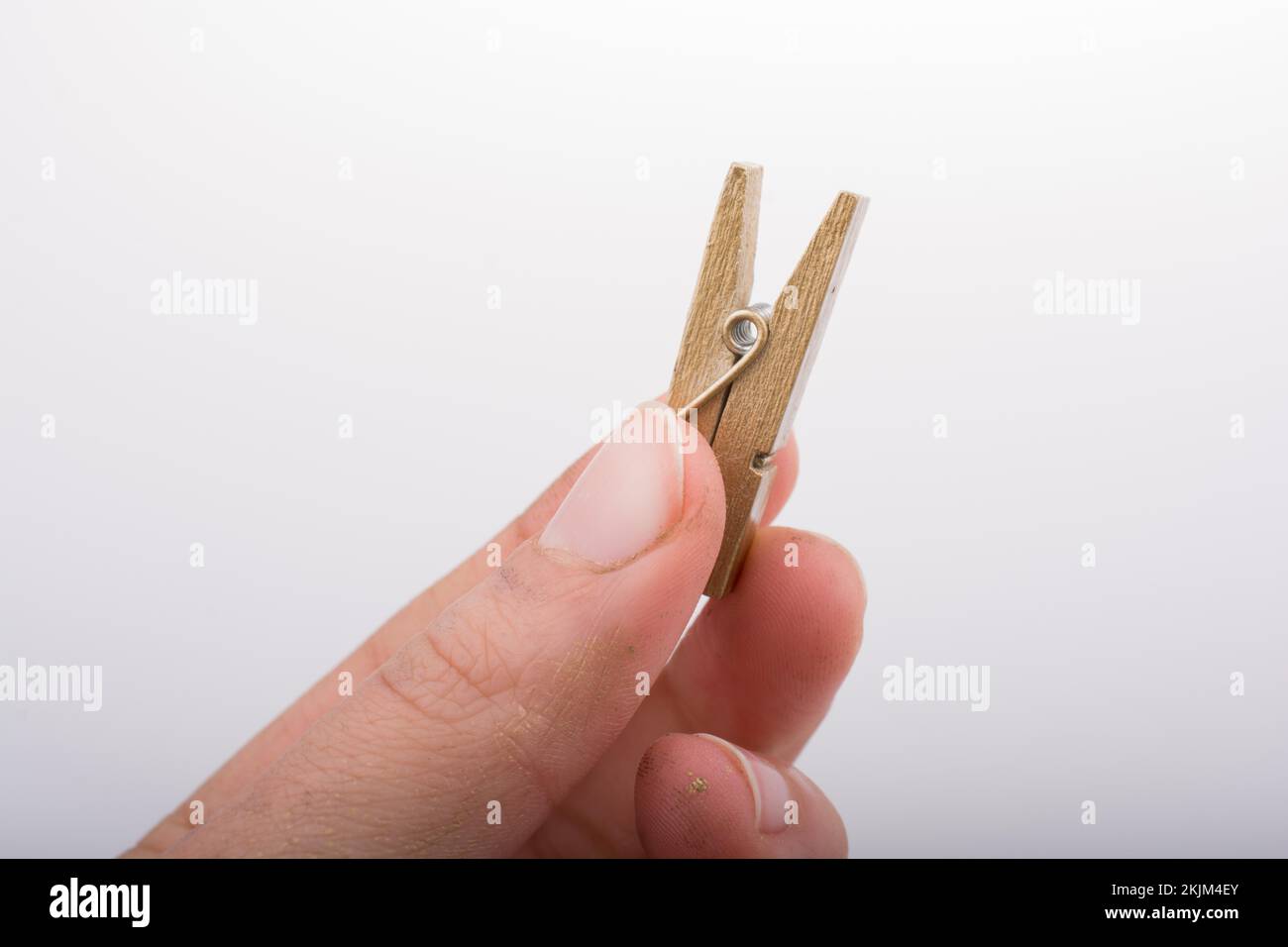 Hand holding a small wooden clothespin in hand Stock Photo - Alamy