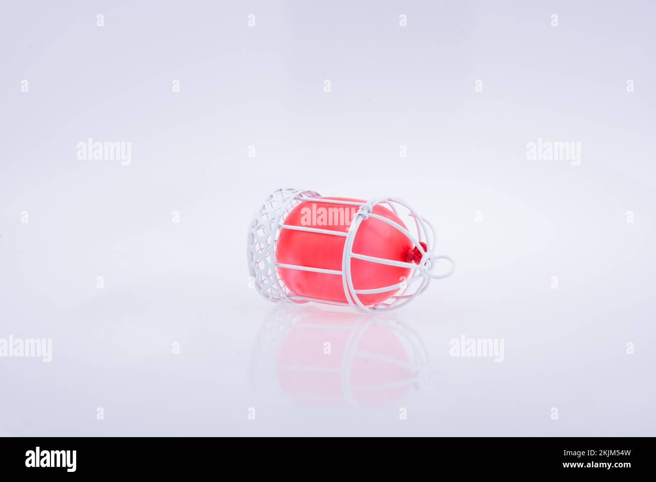 Little red balloon placed in a white color bird house with metal bars ...