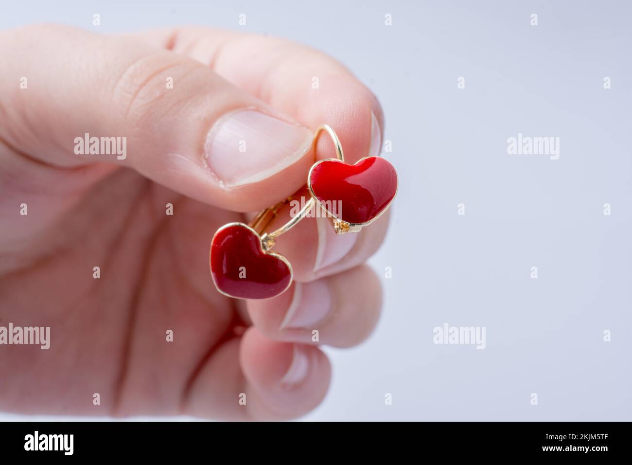 Red color heart shape earring in hand on white Stock Photo - Alamy