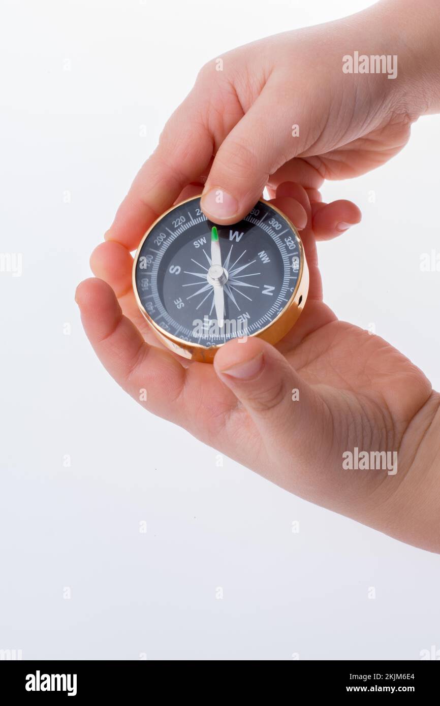 Child hand holding a compass on a white background Stock Photo - Alamy