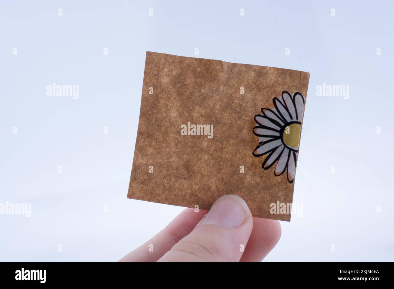 Hand holding a note paper with a floral pattern on a white background ...