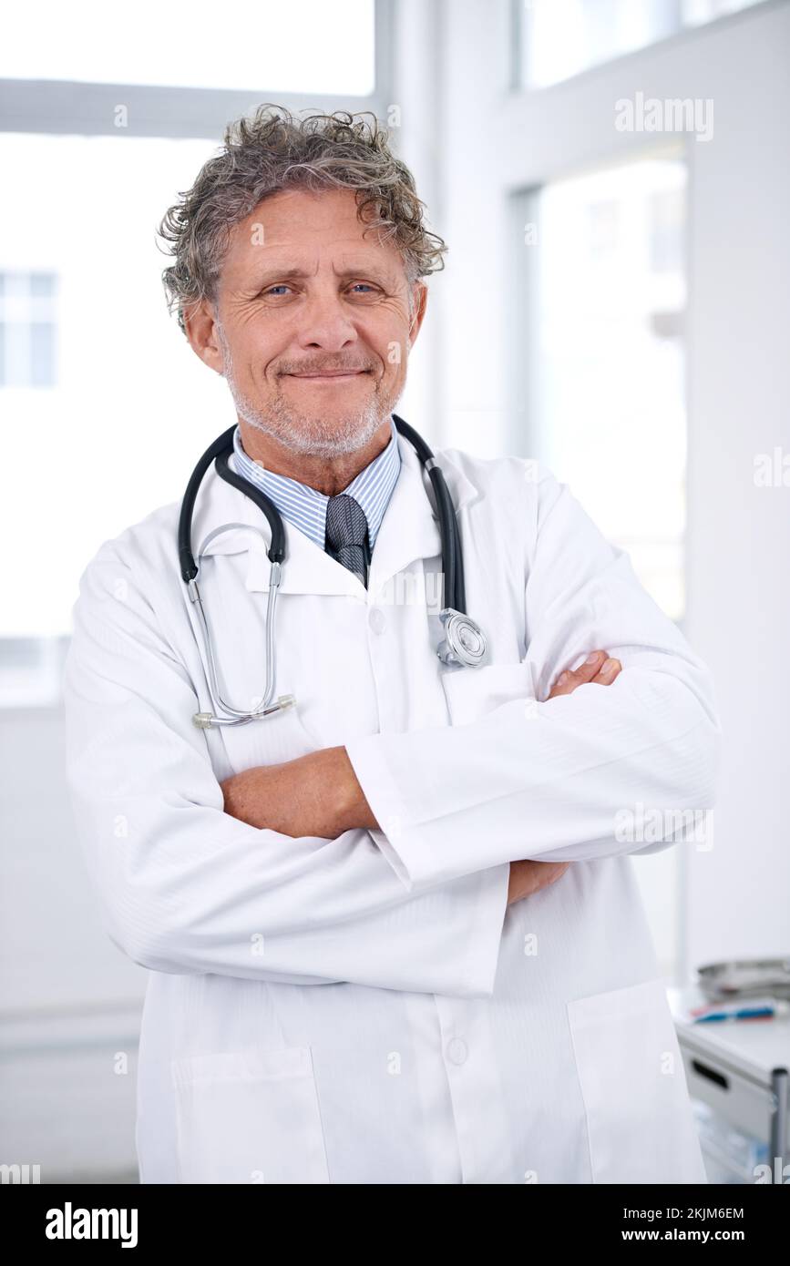 Hes a hero of health. Portrait of a smiling mature doctor standing in ...