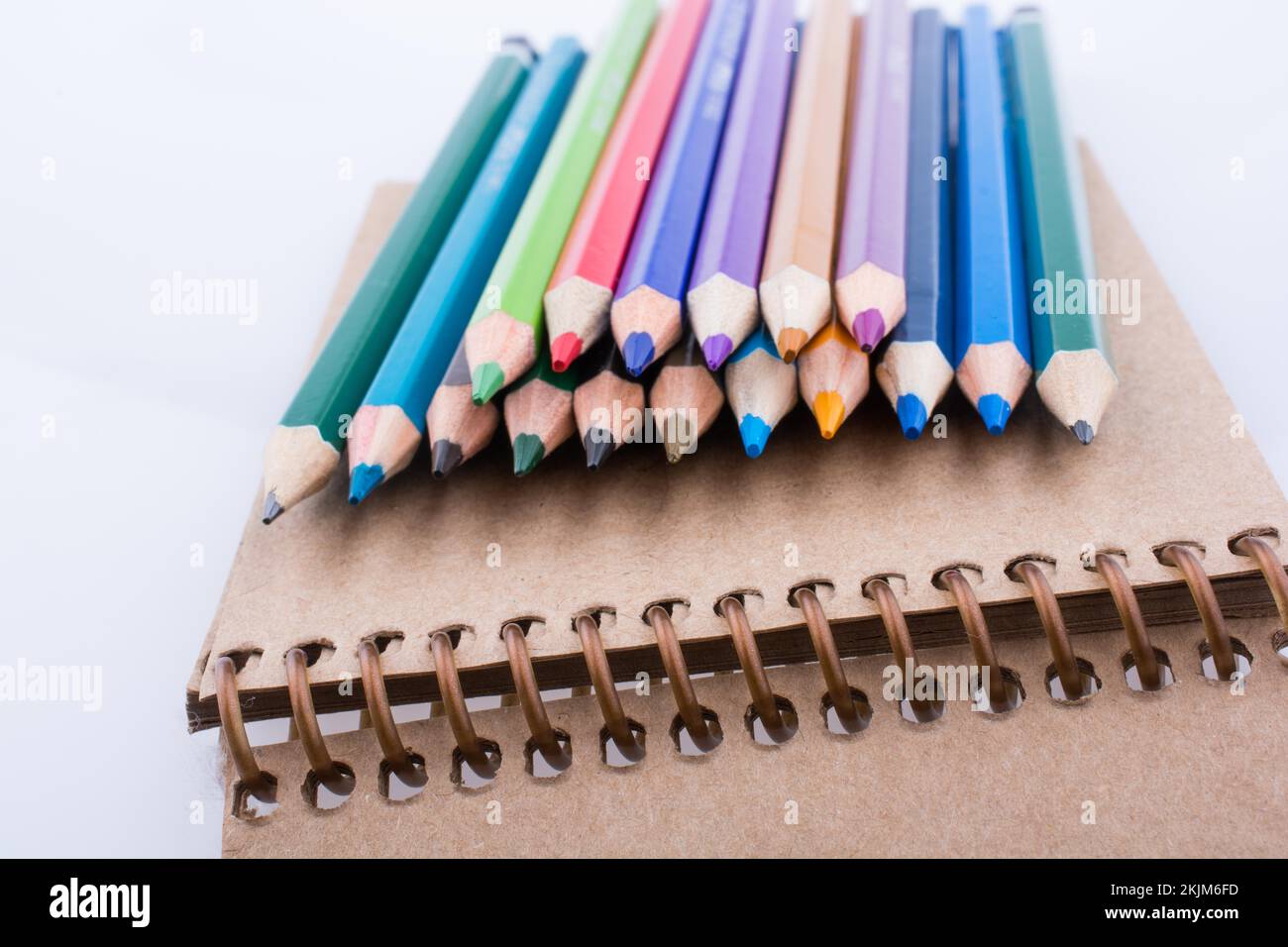 Color pencils placed on a spiral brown notebook Stock Photo - Alamy