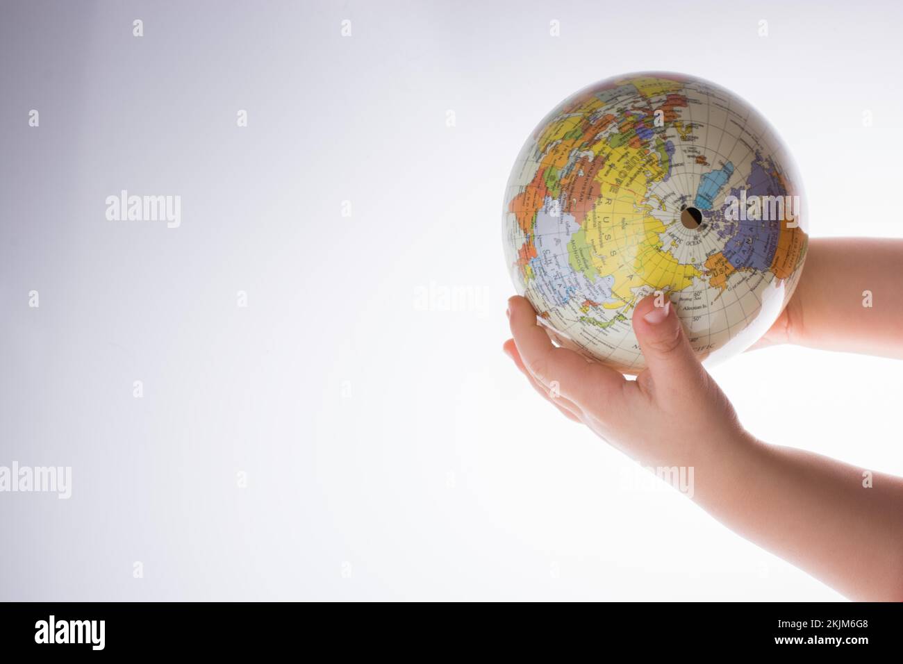 Child holding a globe in on a white background Stock Photo - Alamy