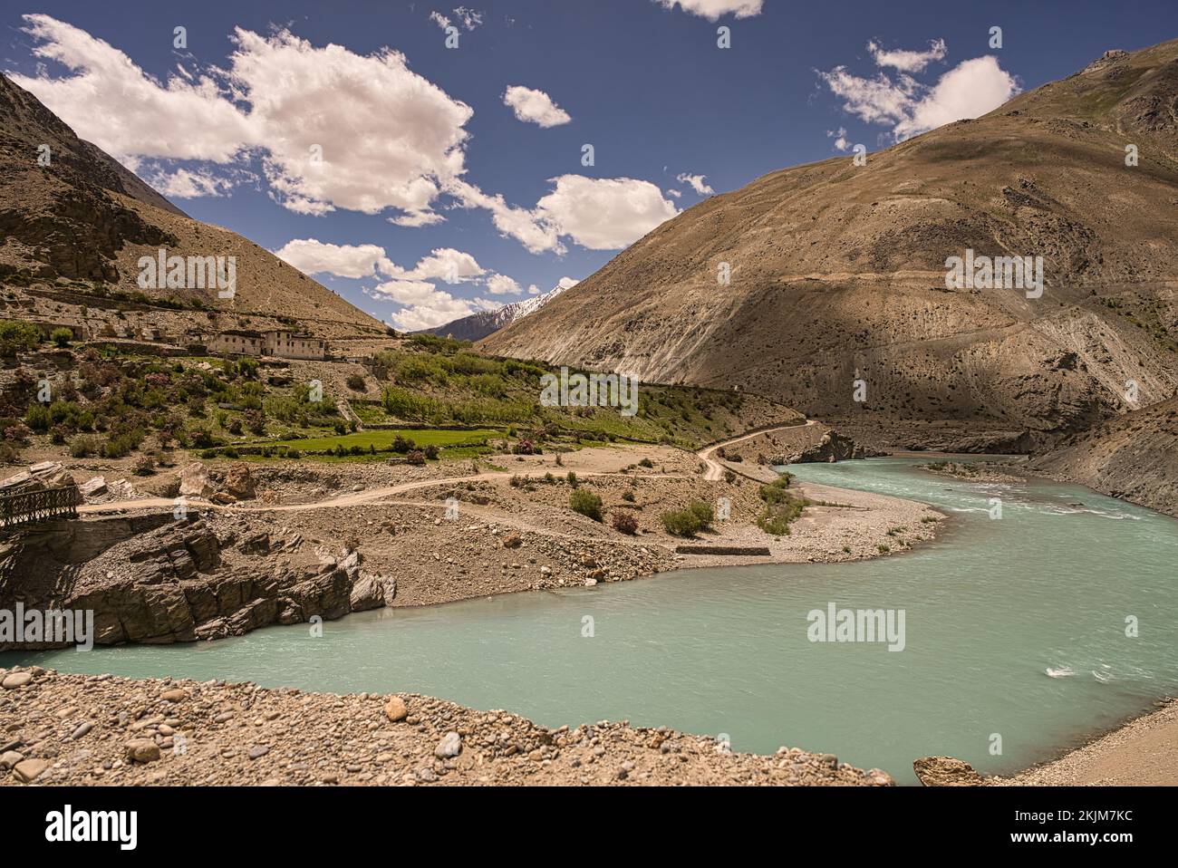 Three adult humans stand with their back to camera in a wide arid ...