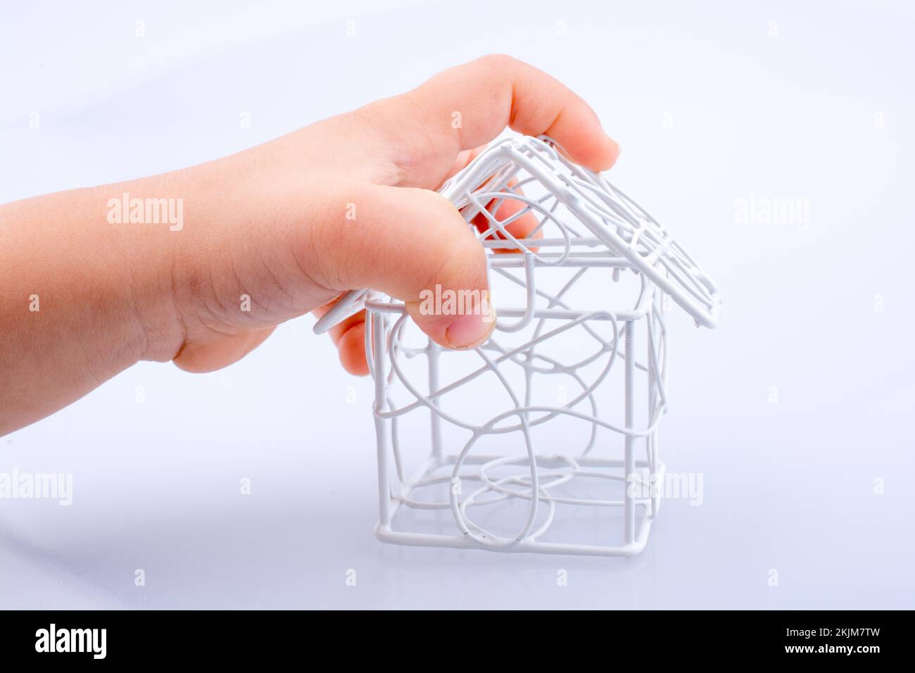 Little model house made of metal bars in hand on a white background ...