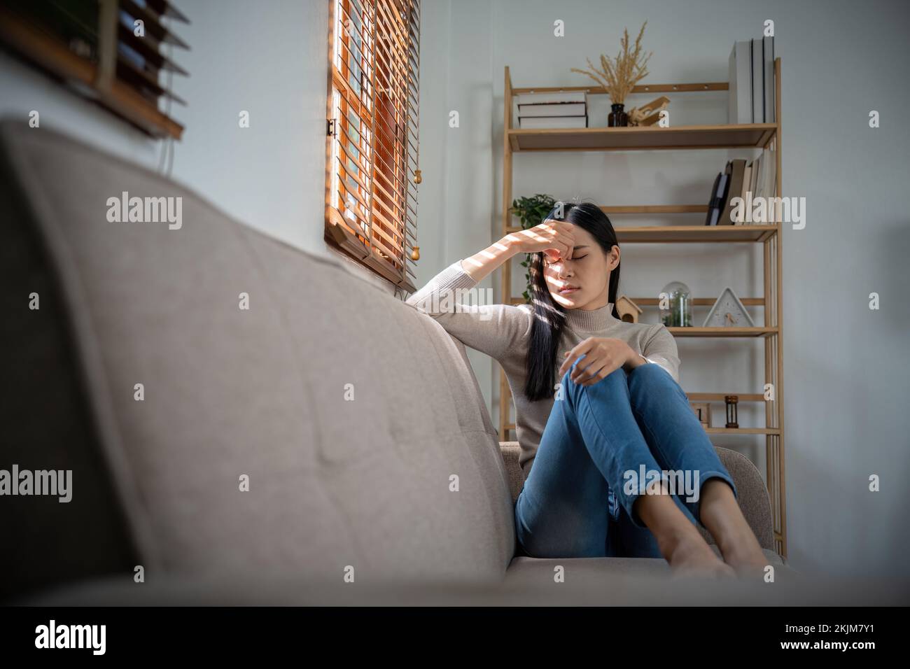 Young lonely attractive asian woman crying on couch feeling sad tired ...