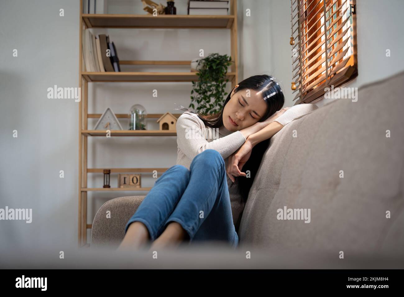 Young lonely attractive asian woman crying on couch feeling sad tired ...