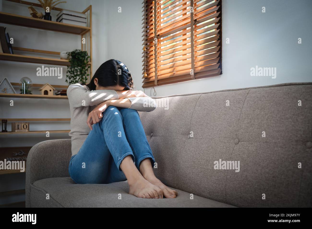 Young lonely attractive asian woman crying on couch feeling sad tired ...