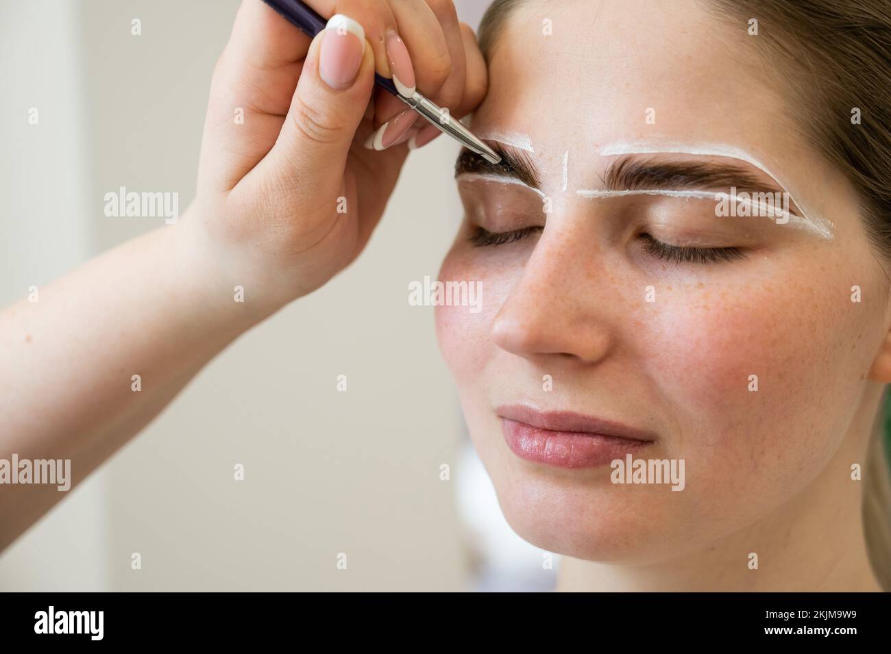 The master draws the shape of the eyebrows with white paint before ...