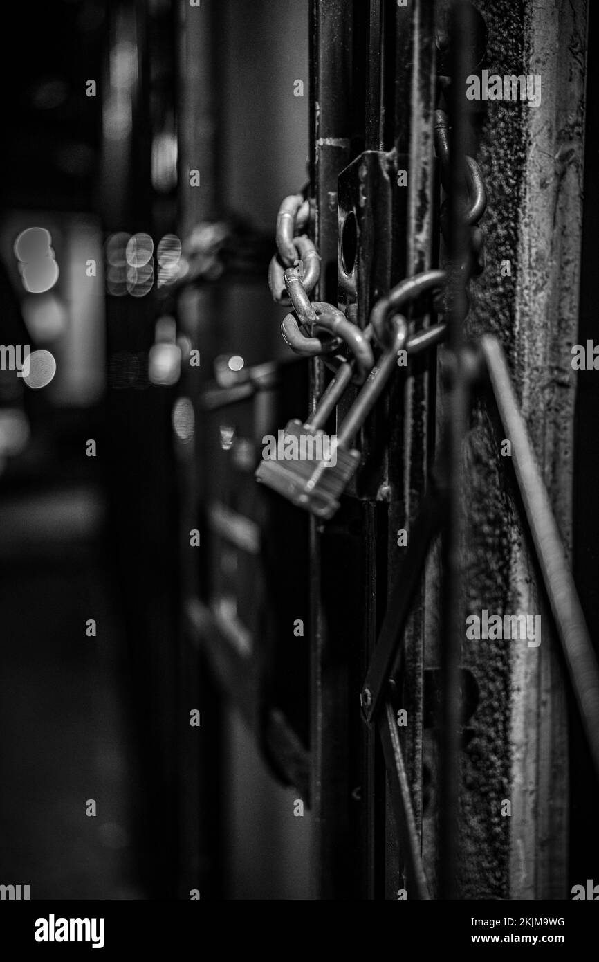 A vertical grayscale of a lock and a chain captured in the dark street ...