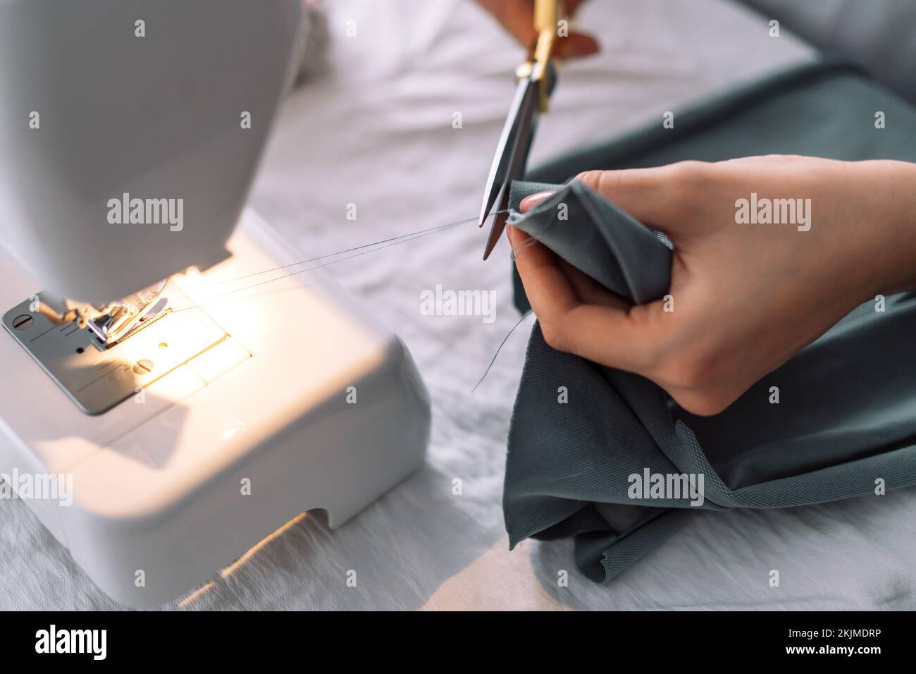 Lady cuts a thread from a sewing machine with scissors Stock Photo - Alamy