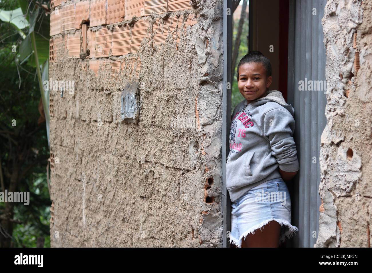 Favela, girl looking out of the front door of her house, Belo Horizonte ...