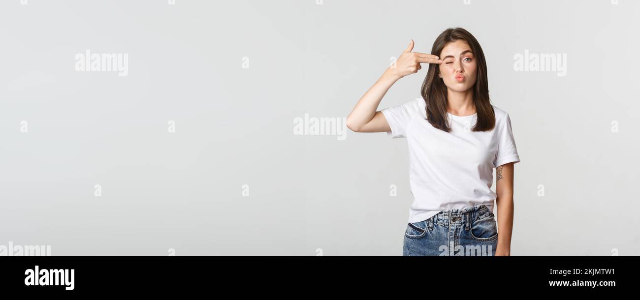 Unamused cute girl grimacing and showing hand gun gesture at head Stock ...