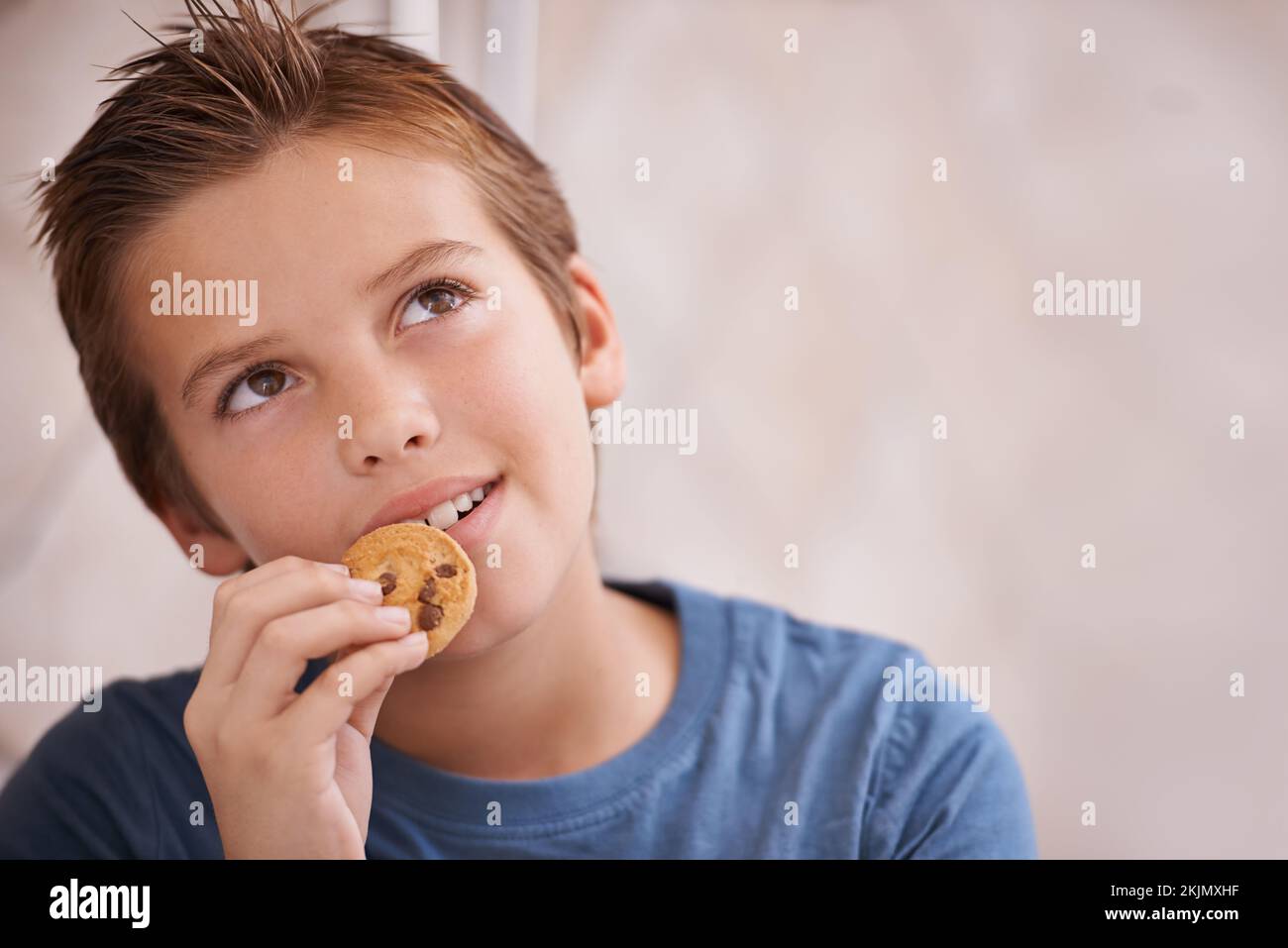 This is beyond delicious. a young boy lost in thought while biting into ...